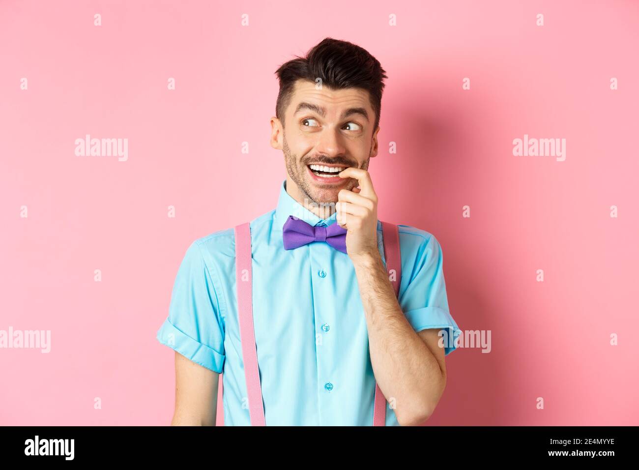 Image of smiling man making choice, looking dreamy and happy aside ...