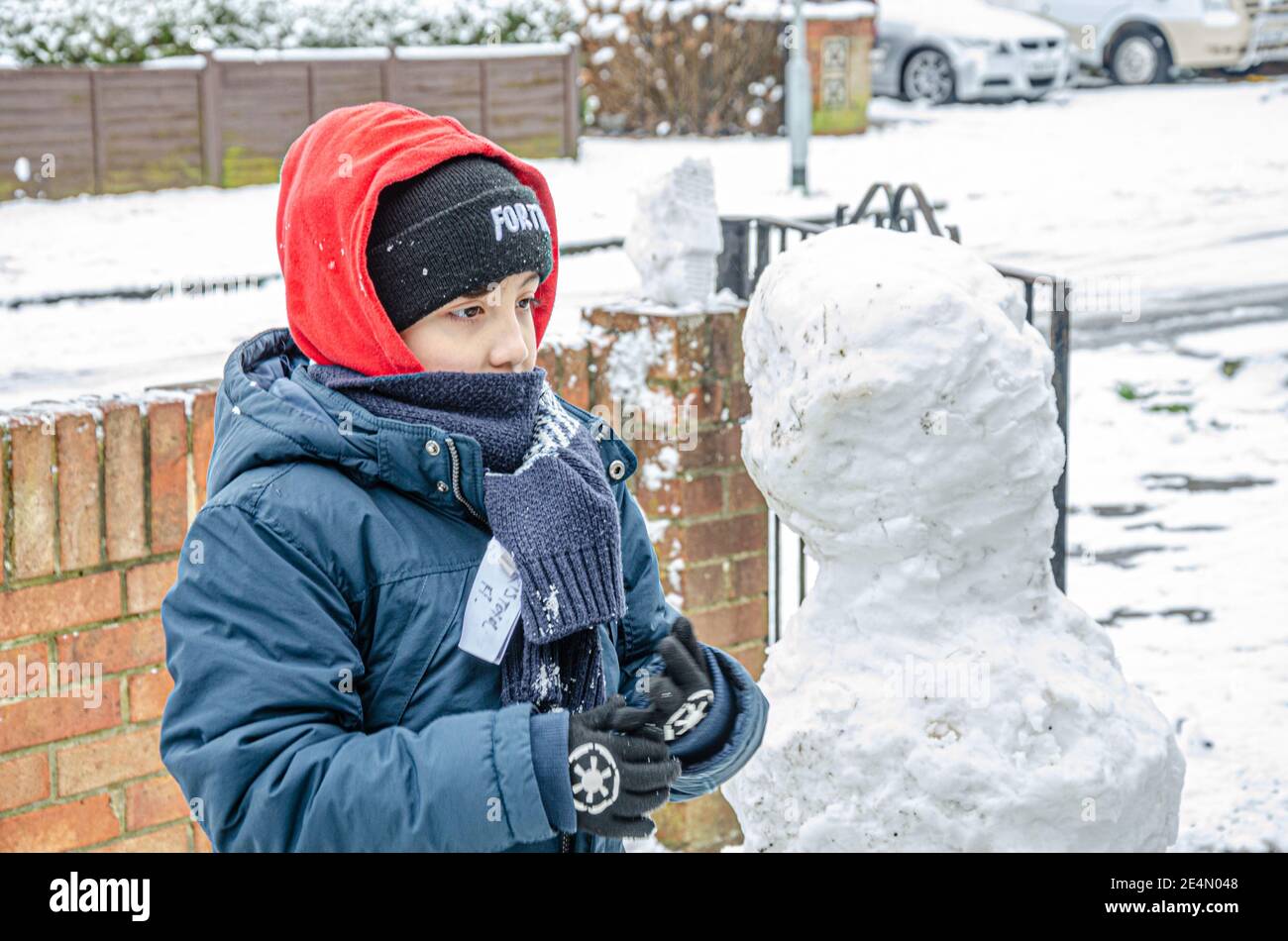 Children building a snowman out of snow in a front garden in Reading ...