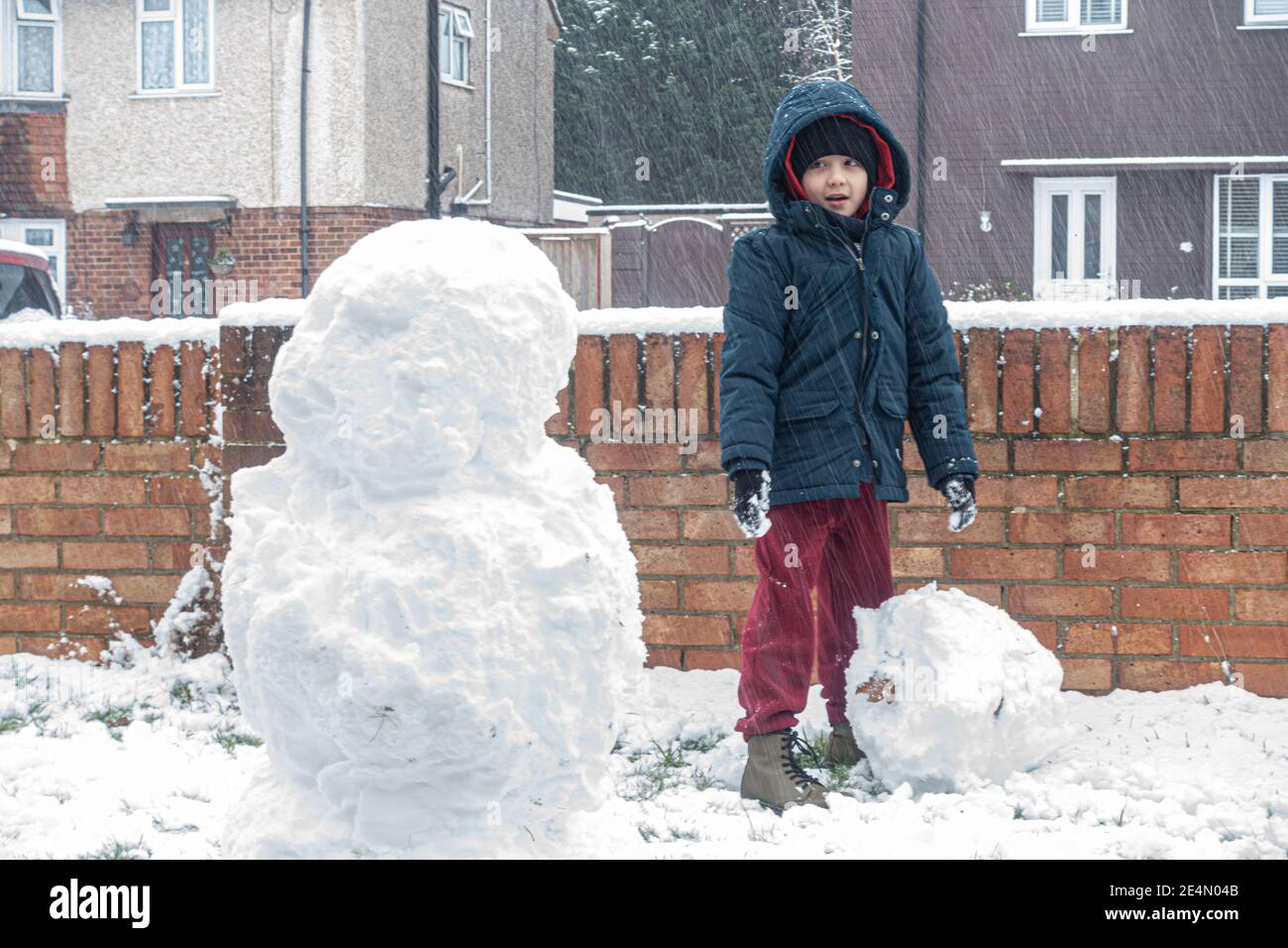 Children building a snowman out of snow in a front garden in Reading ...
