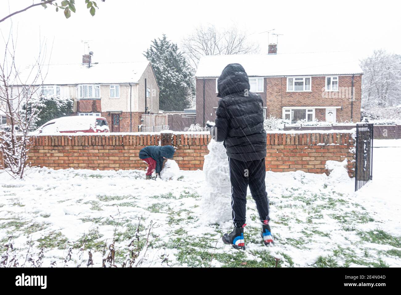 Children building a snowman out of snow in a front garden in Reading ...