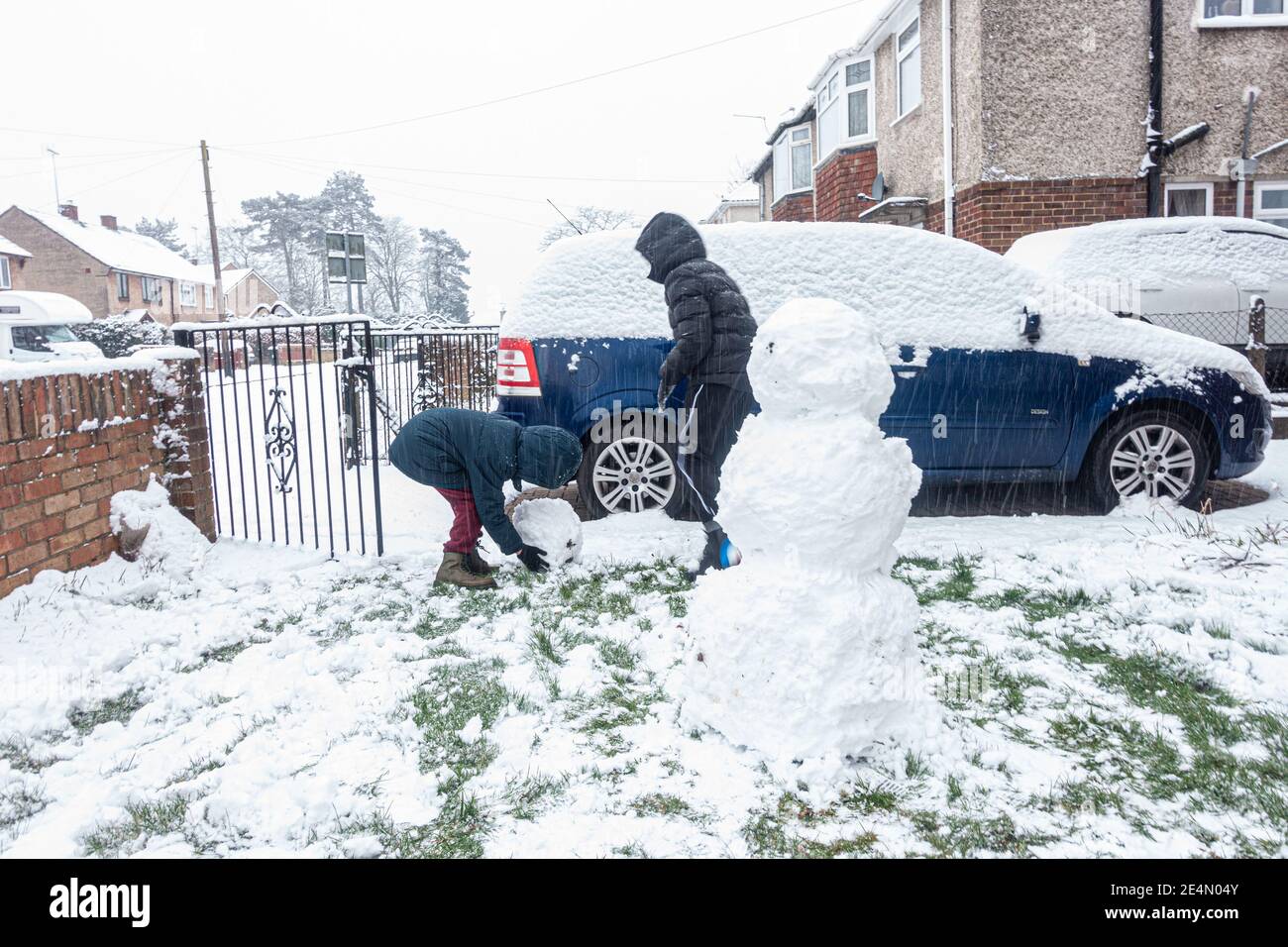 Children building a snowman out of snow in a front garden in Reading ...