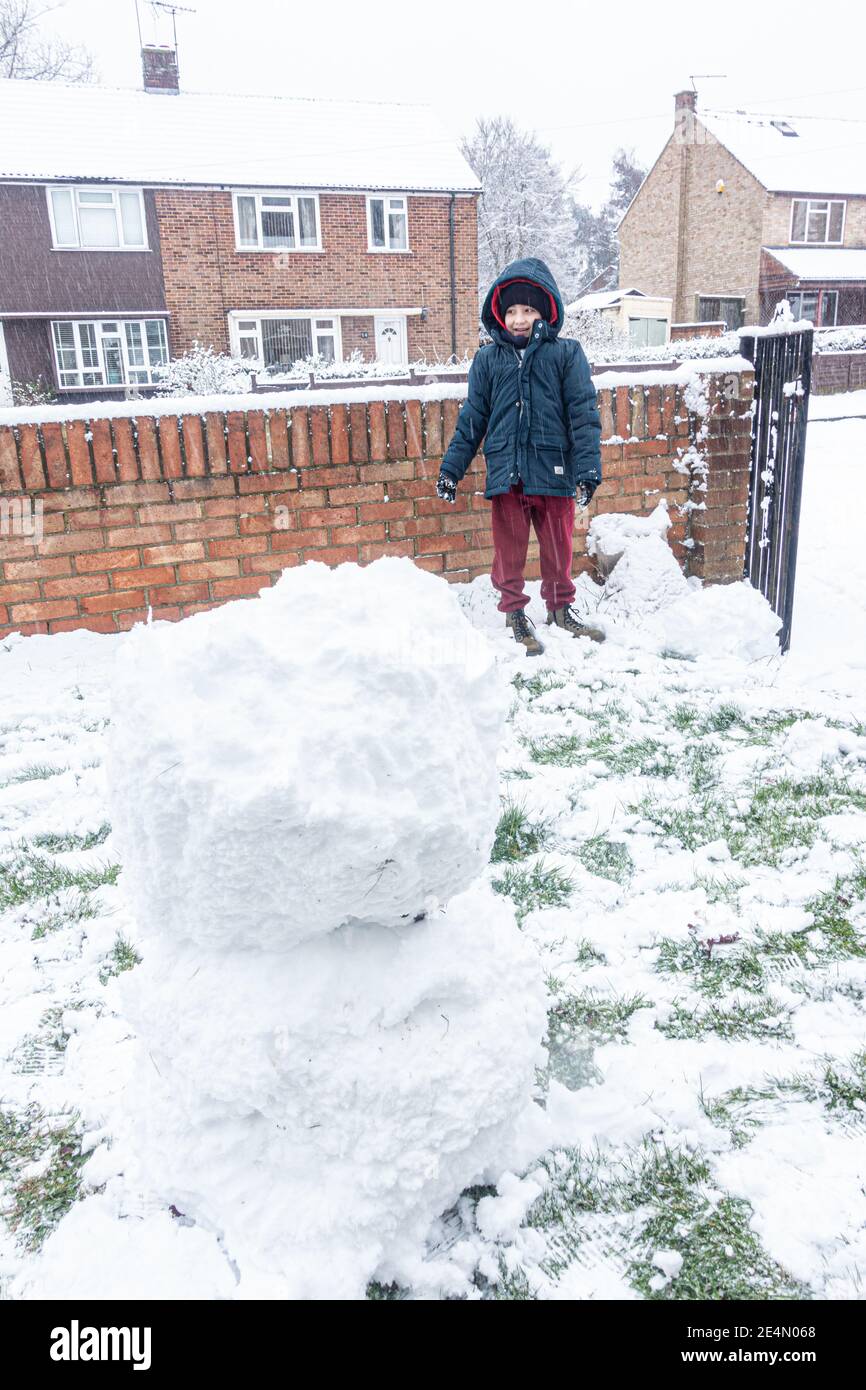 Children building a snowman out of snow in a front garden in Reading ...