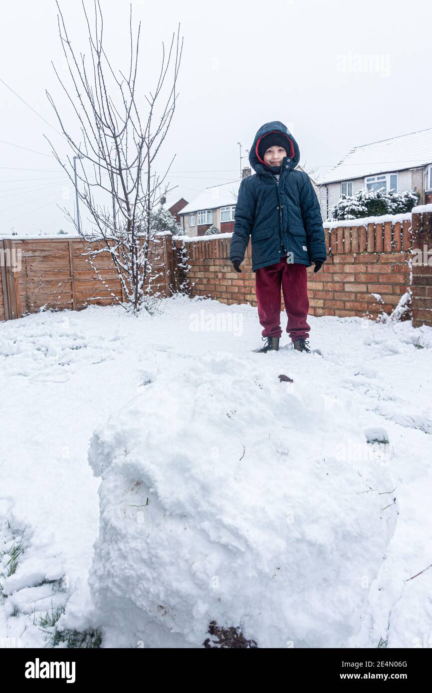 Children building a snowman out of snow in a front garden in Reading ...