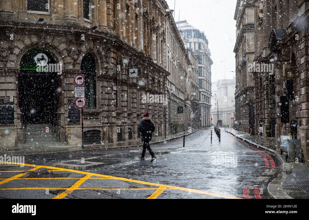A lady crossing the street during snow fall across the capital Stock ...