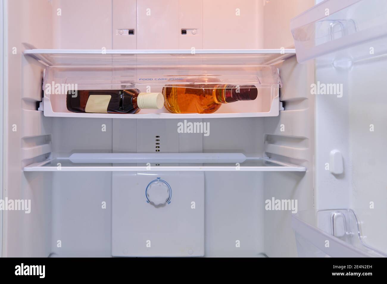 Alcohol bottles in empty fridge. Two bottles of whiskey on the shelf ...