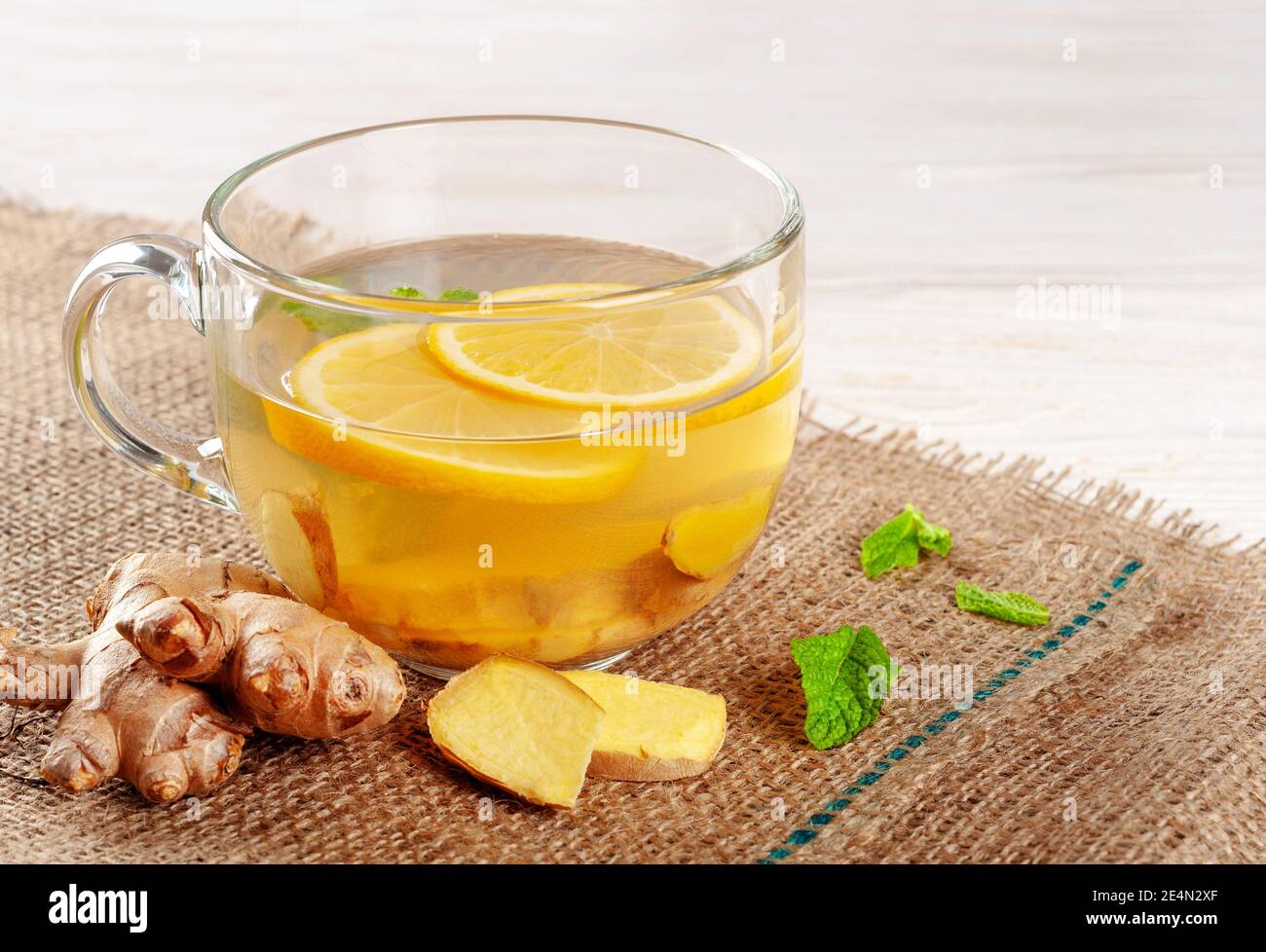 Glass cup of hot ginger tea with lemon and peppermint. Winter herbal ...