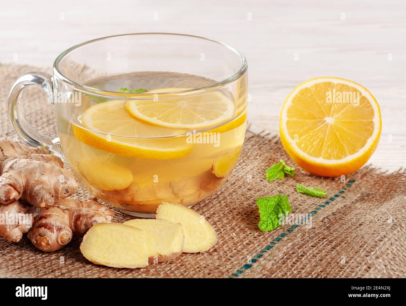 Glass cup of hot ginger tea with lemon and peppermint. Winter herbal ...