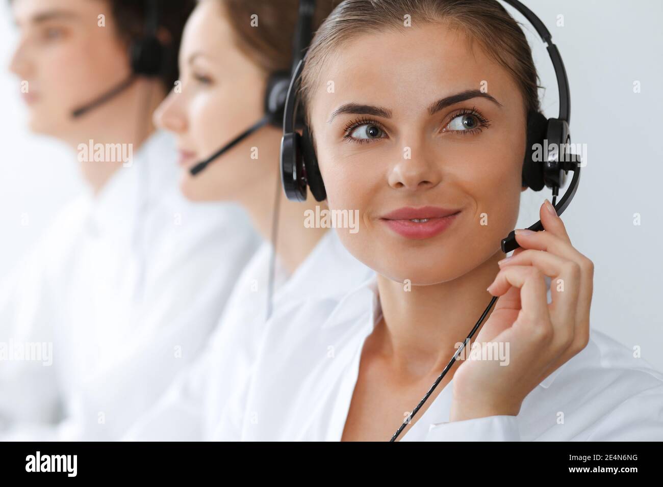 Call center. Beautiful young woman using headset and computer to help ...