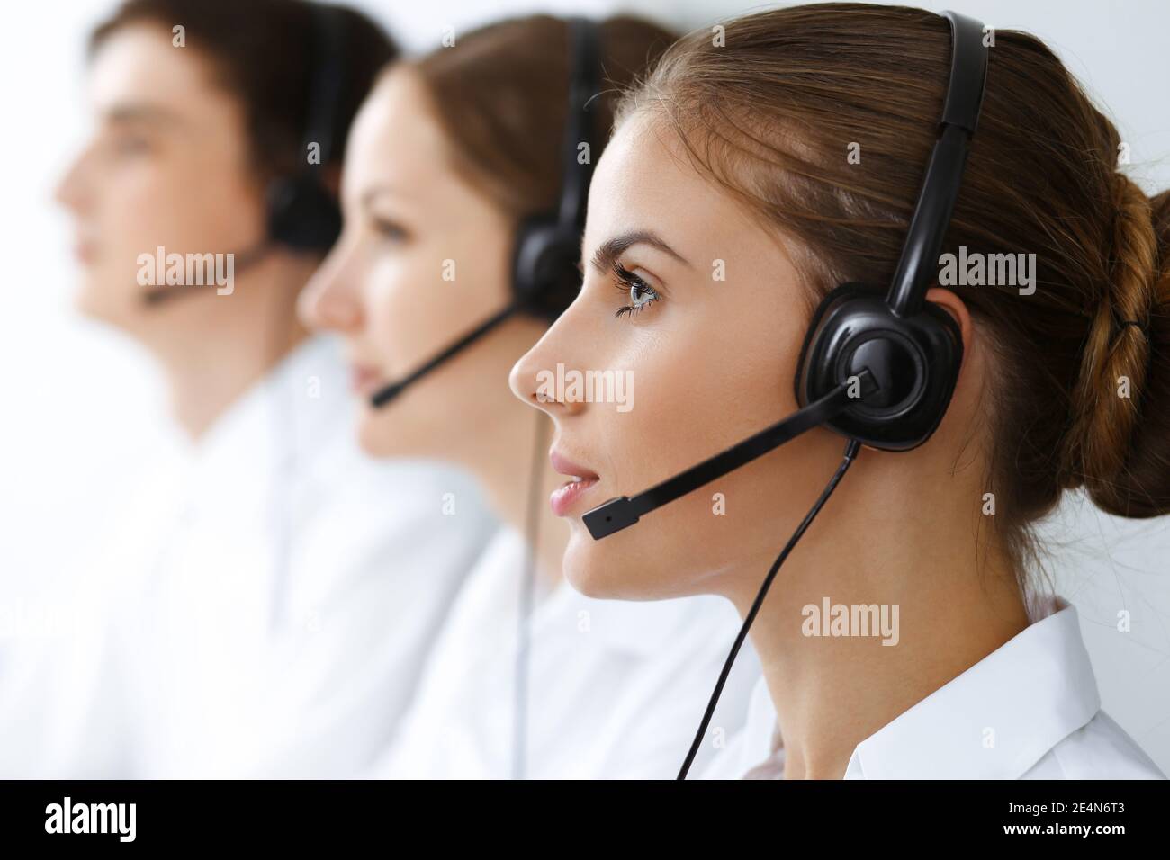 Call center. Beautiful young woman using headset and computer to help ...