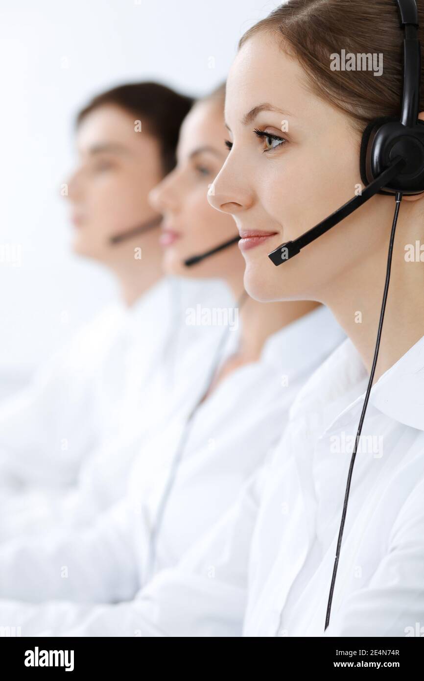 Call center. Beautiful young woman using headset and computer to help ...