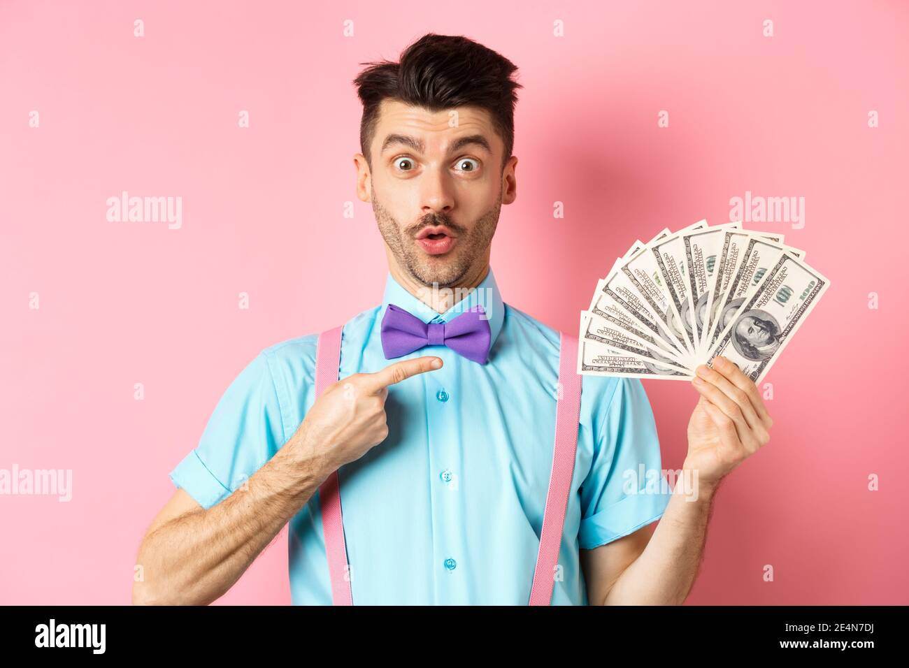 Amazed man showing big money prize, pointing at dollars and say wow ...