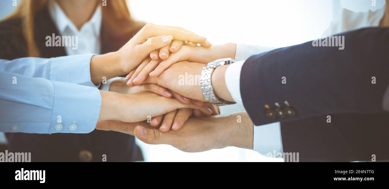 Business team showing unity with their hands together in sunny office ...