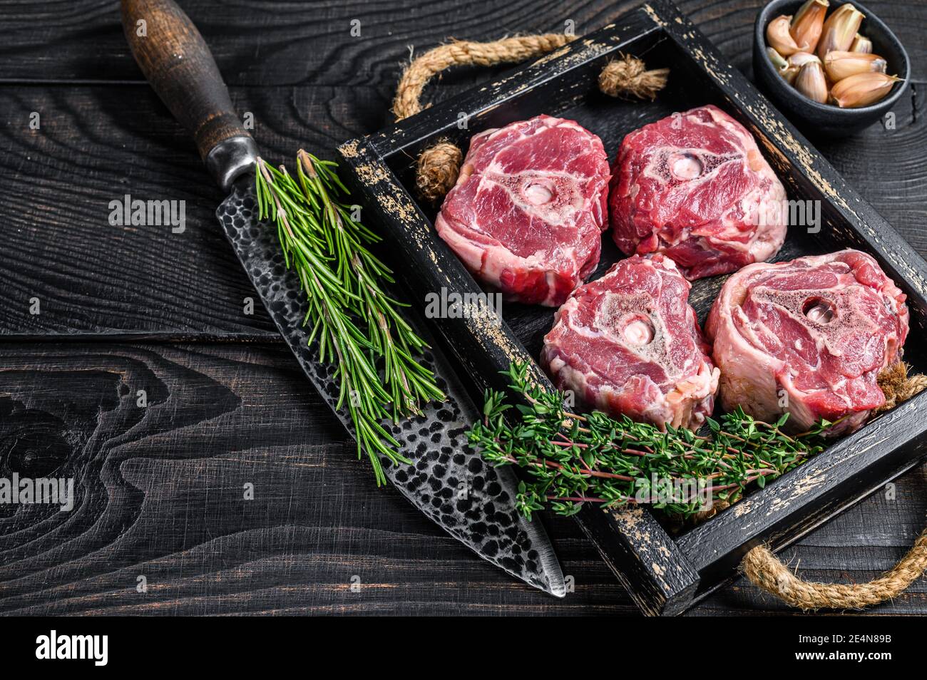 Raw lamb neck meat on a butcher table with knife. Black wooden ...