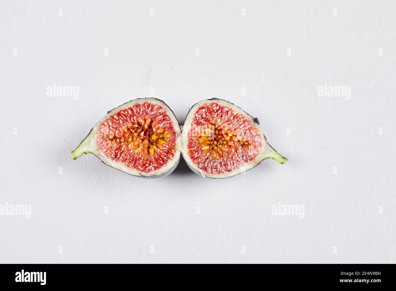 Half slices of ripe fig on a white background Stock Photo - Alamy