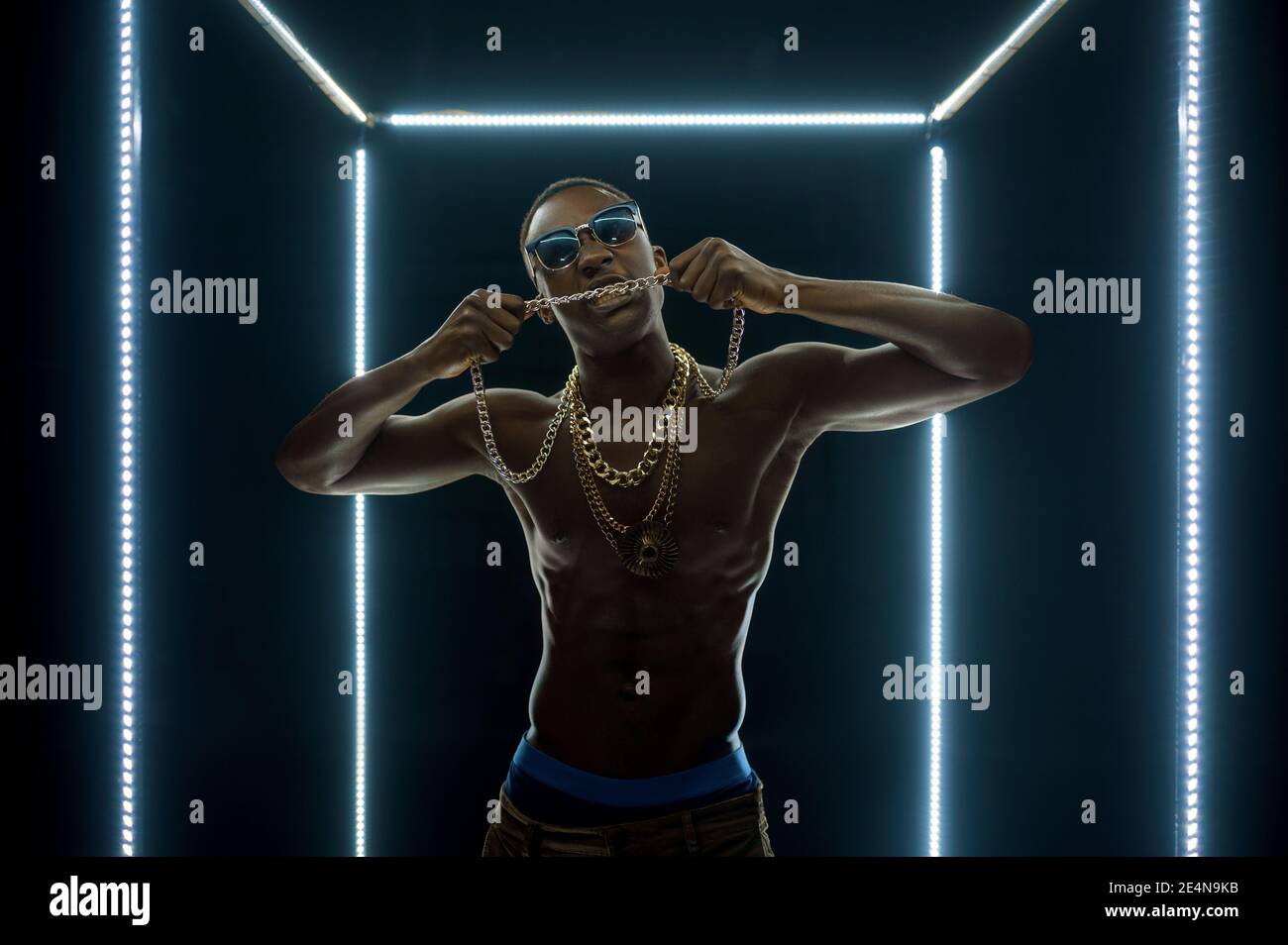 Rapper in gold chains poses in illuminated cube Stock Photo - Alamy