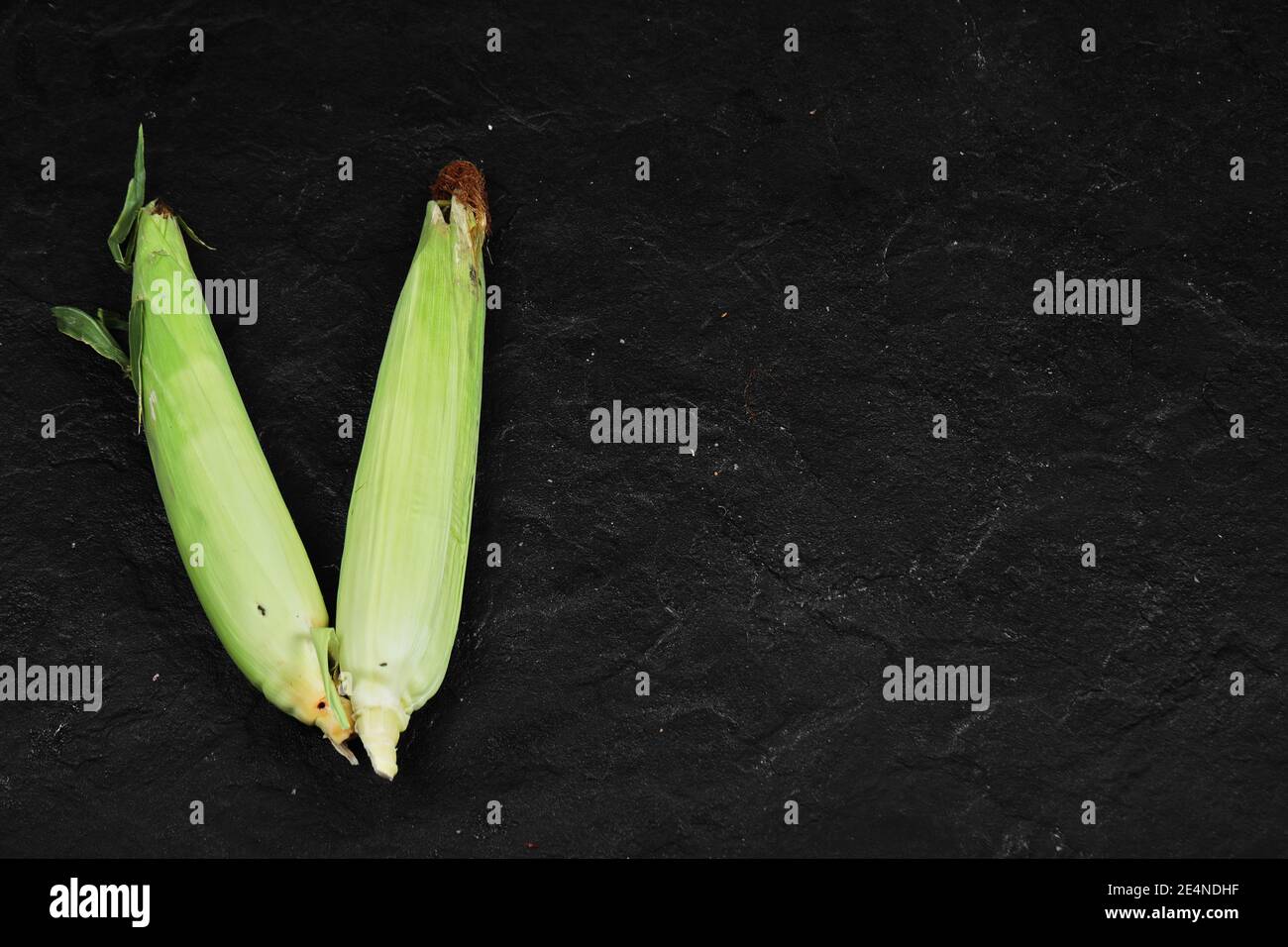 Two ears of fresh corns on black background Stock Photo - Alamy