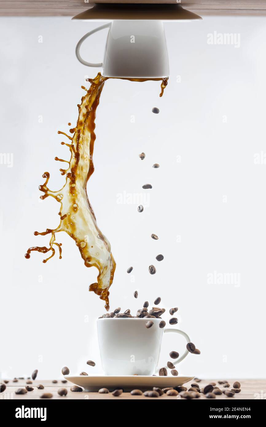 Splashing of coffee in white cup and falling coffee beans on white ...