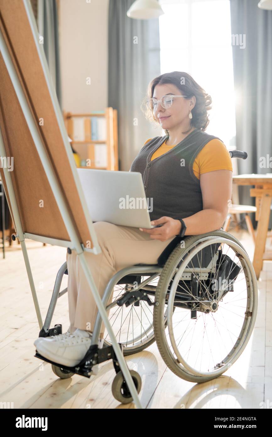Young disable businesswoman looking at laptop display while preparing ...
