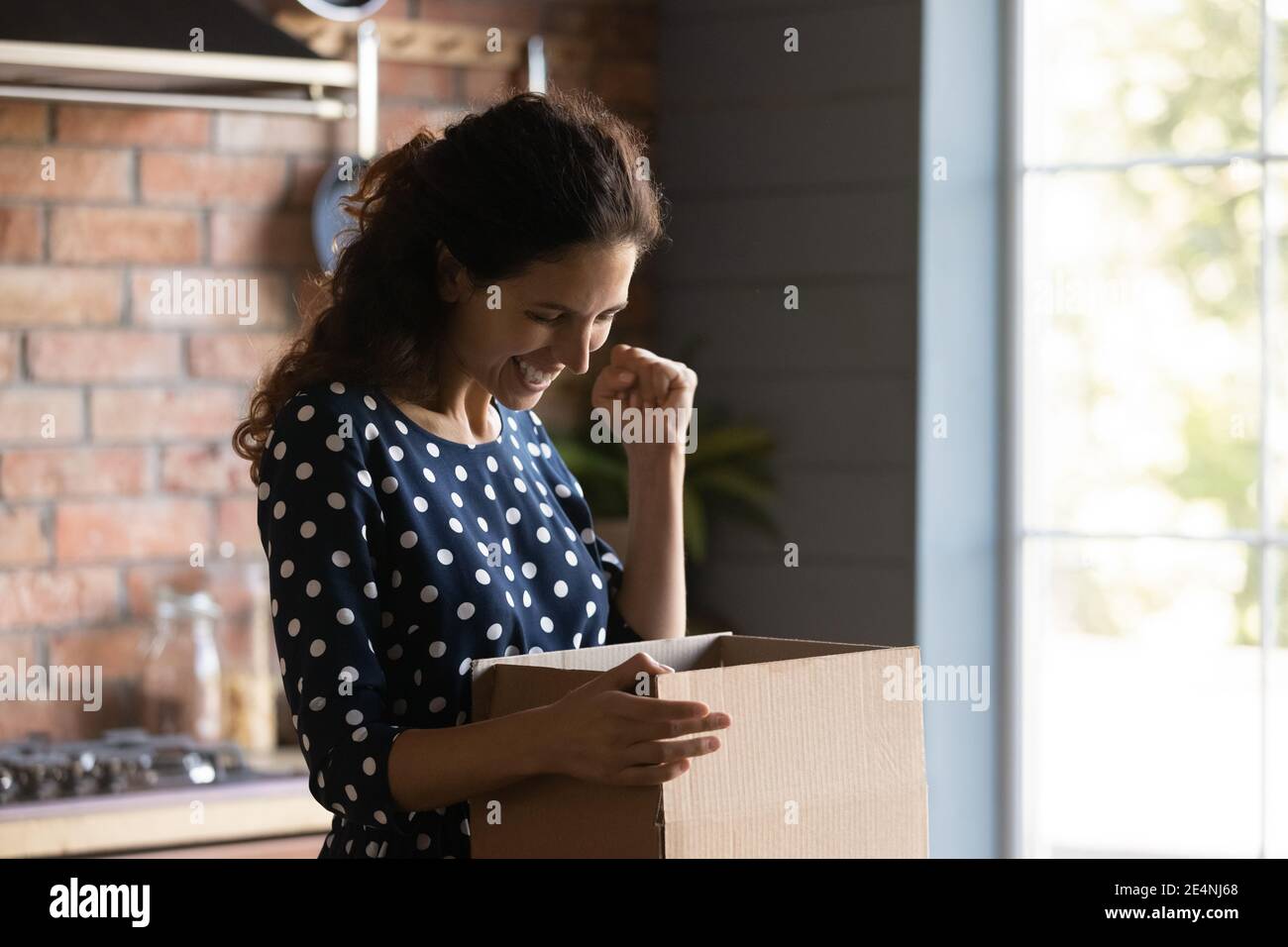 Overjoyed female client unpack box with internet order Stock Photo - Alamy