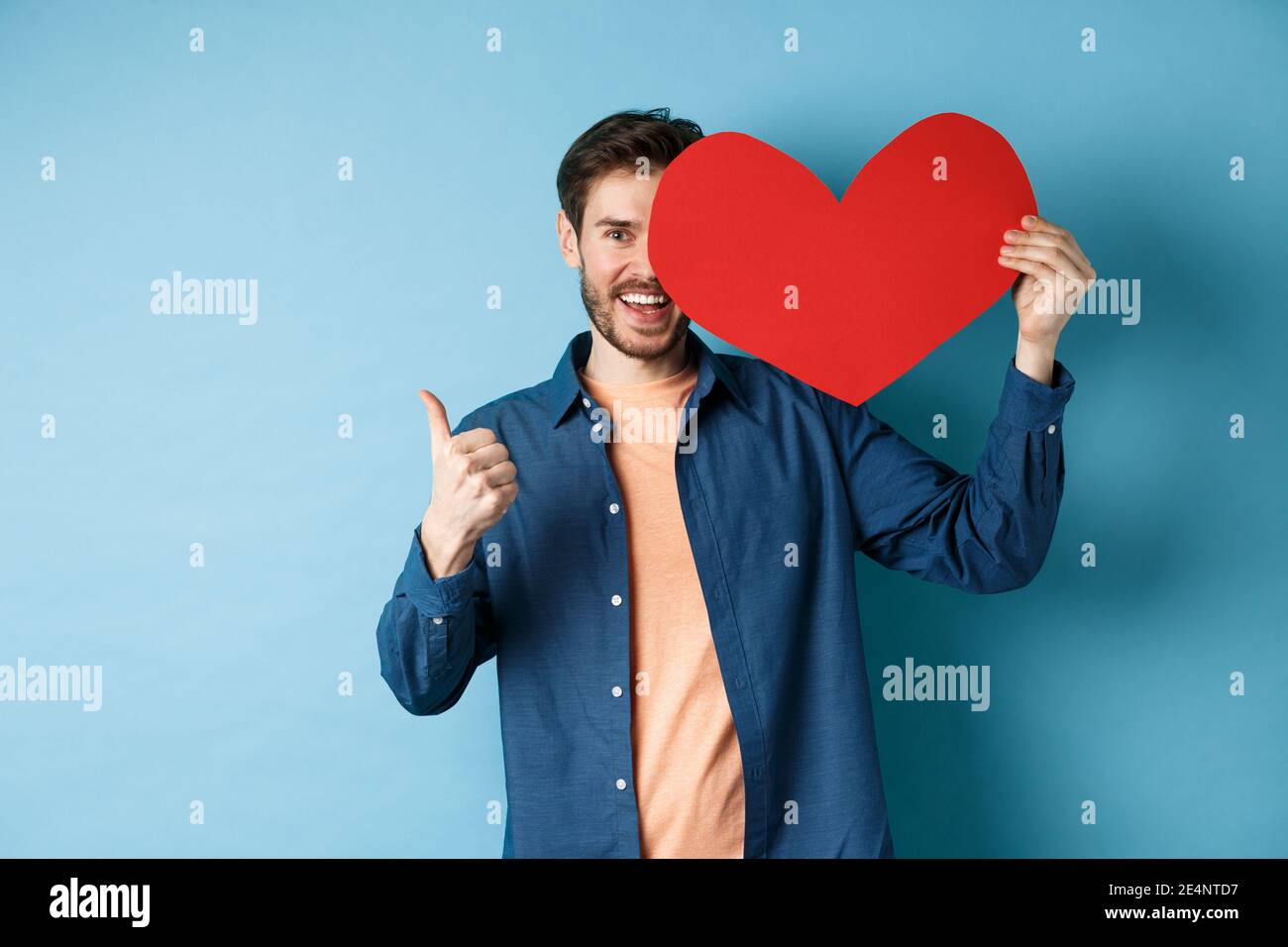Happy man showing valentines heart and thumbs-up gesture, standing over ...