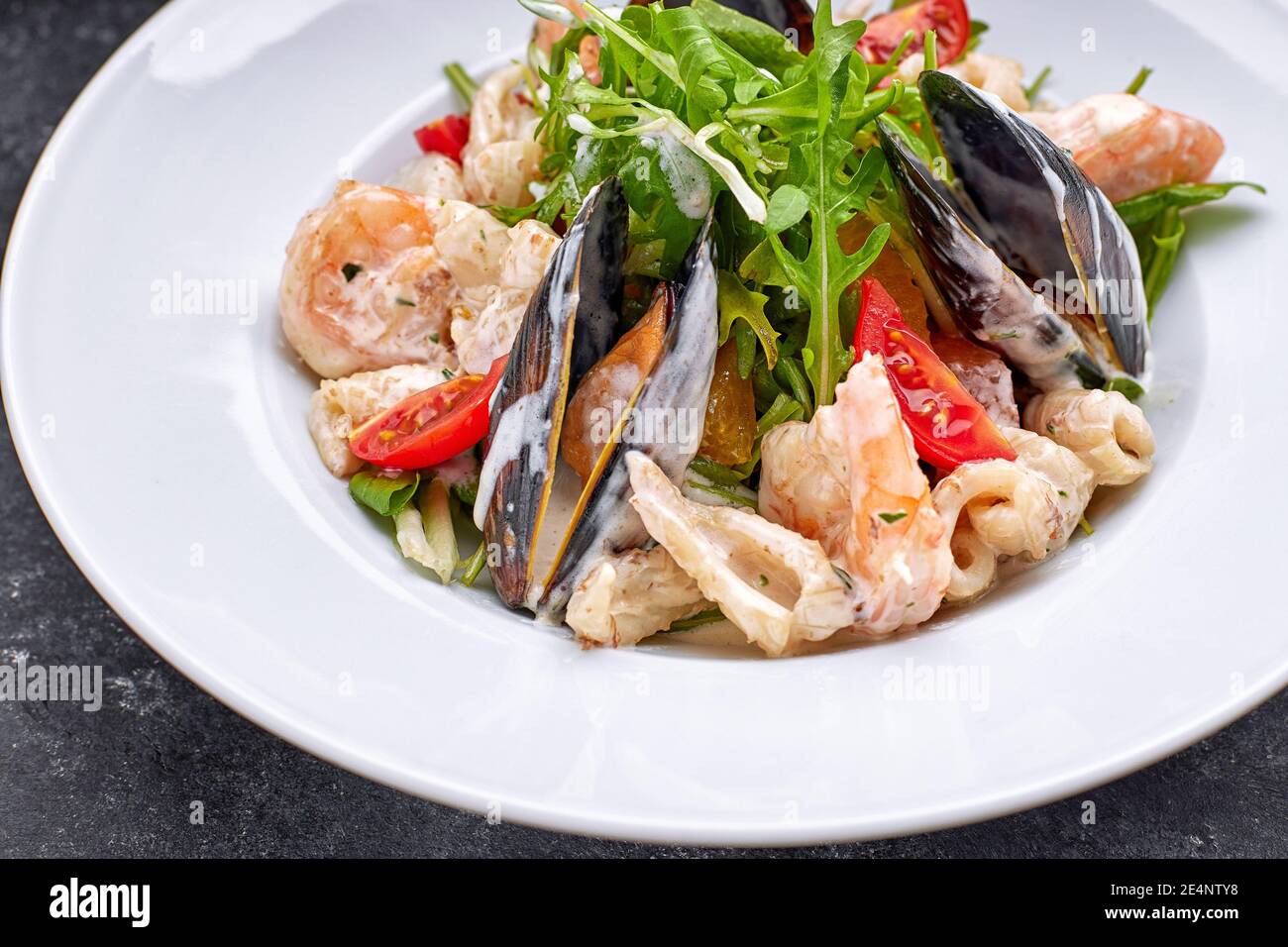 Seafood salad with mussels, squid, shrimp, on a round white plate, on a ...