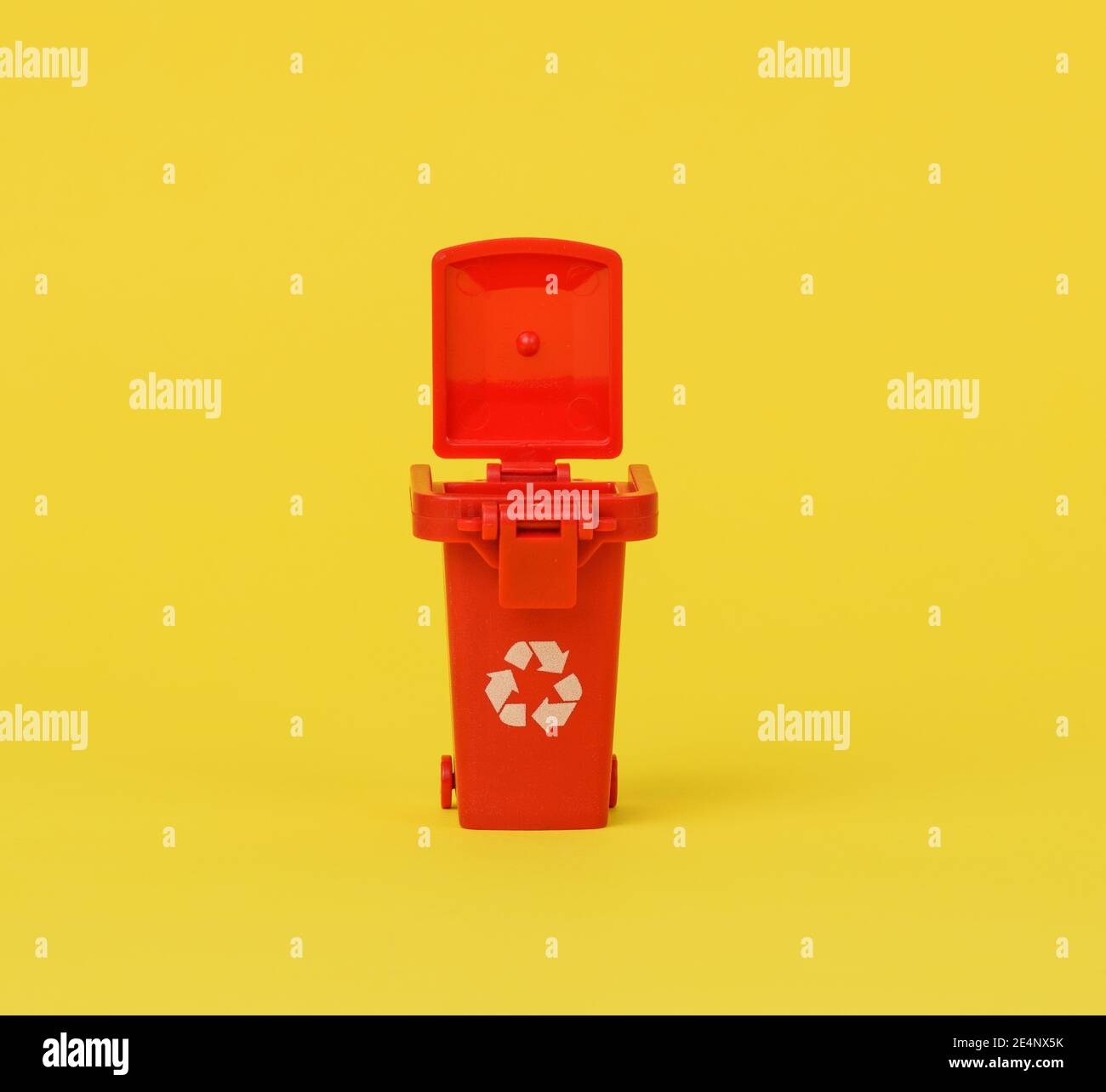 miniature of red plastic waste sorting bin on yellow background, close ...