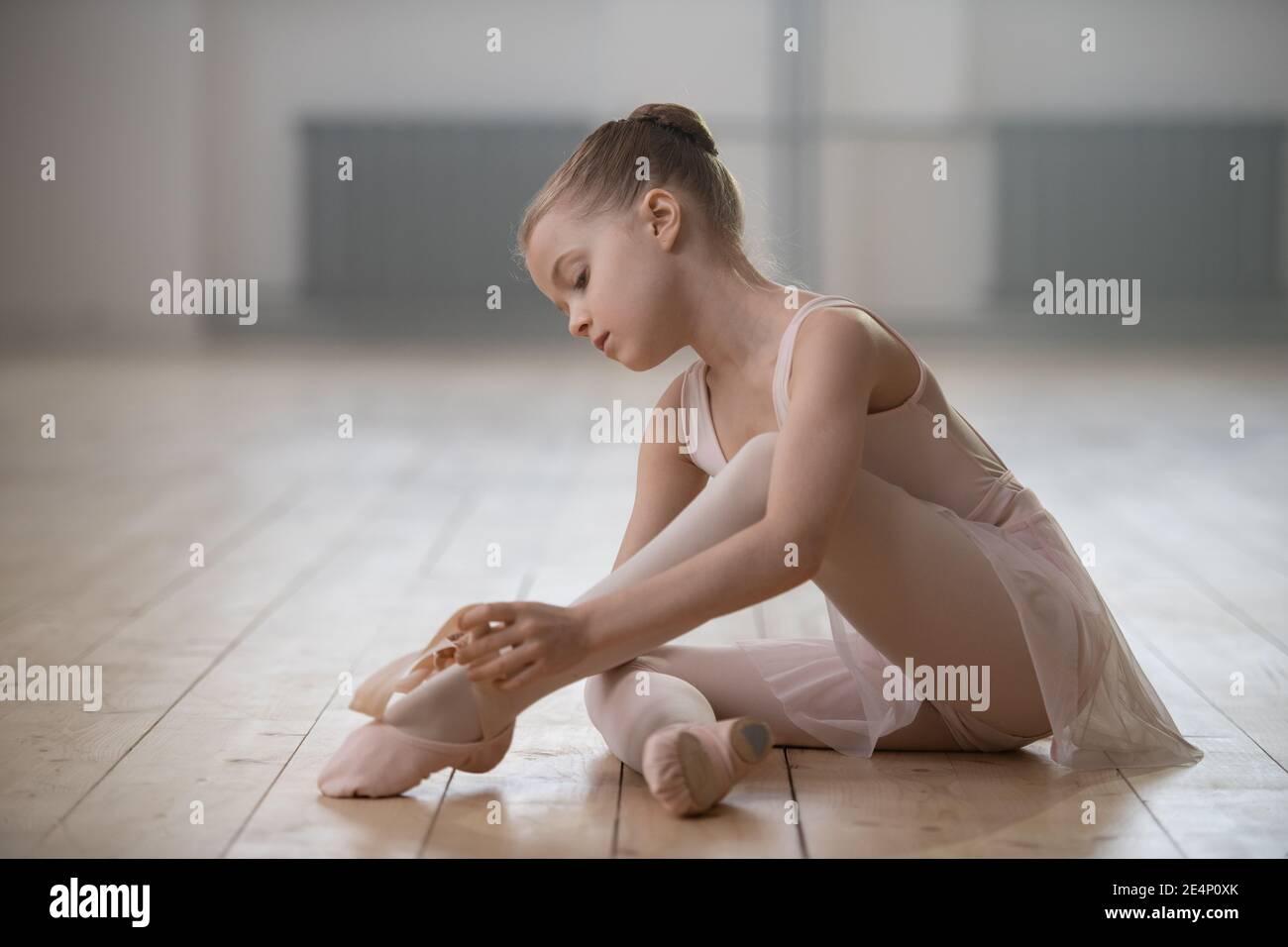 Little ballerina sitting on the floor and preparing for the classes in ...