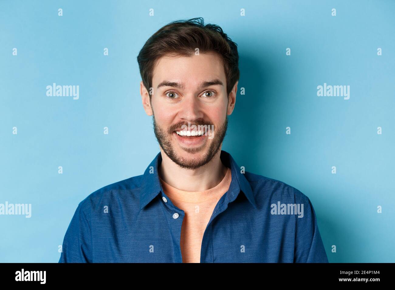 Close up of surprised handsome guy with beard looking amused, smiling ...
