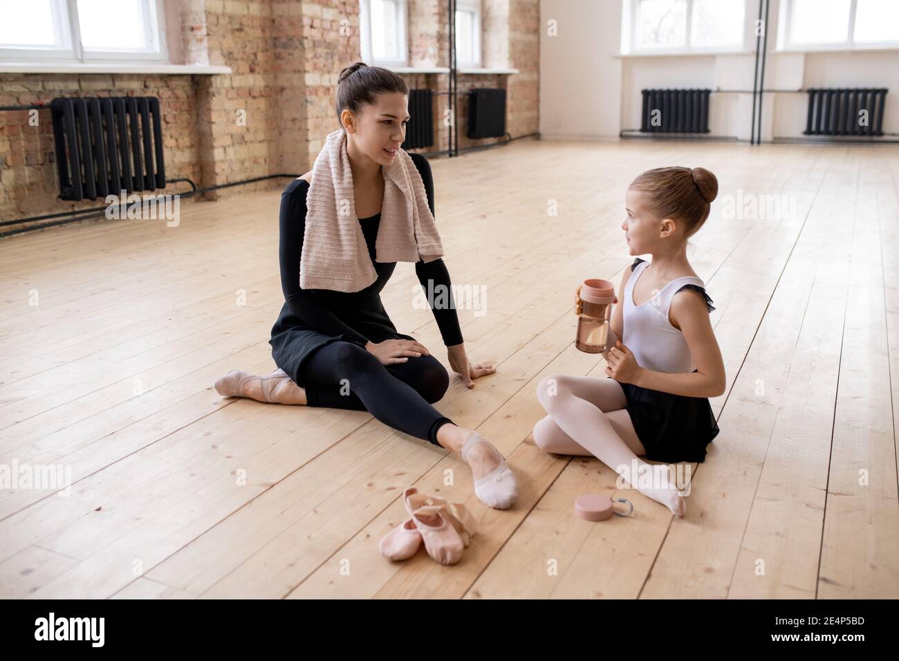 Two ballerinas sitting on the floor after training and discussing the ...
