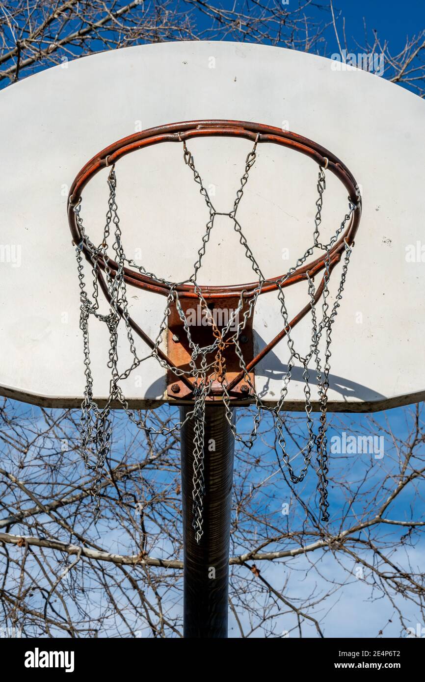 Old basketball hoop with a metal net against blue sky and tree Stock ...