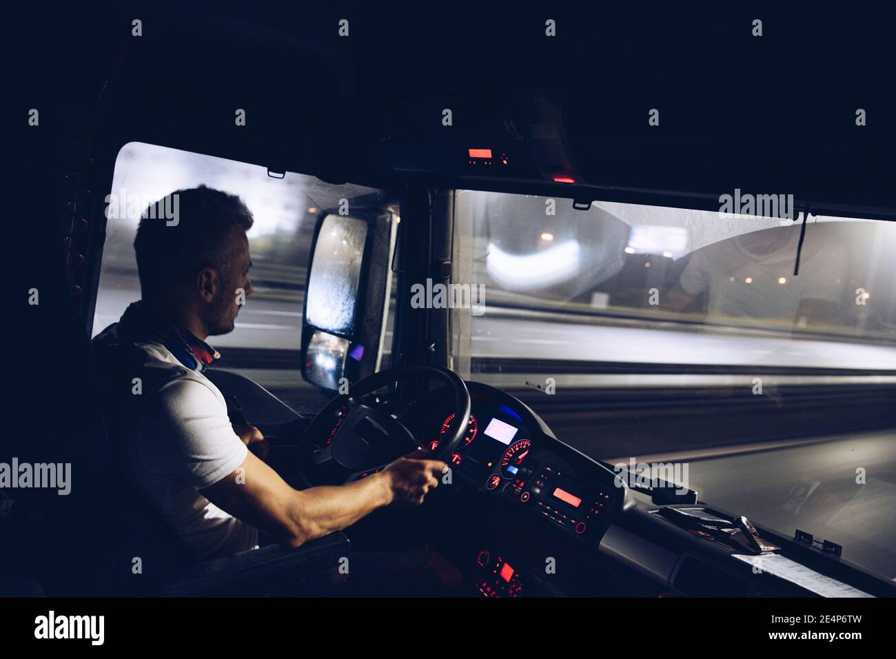 A handsome driver at the wheel of a truck is driving his goods at night ...