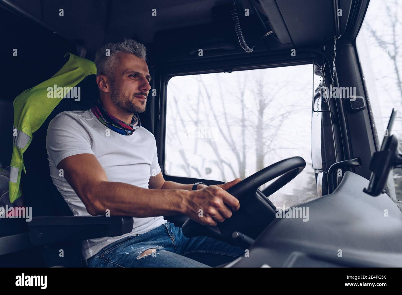 A handsome driver behind the wheel of a truck is driving on the road ...