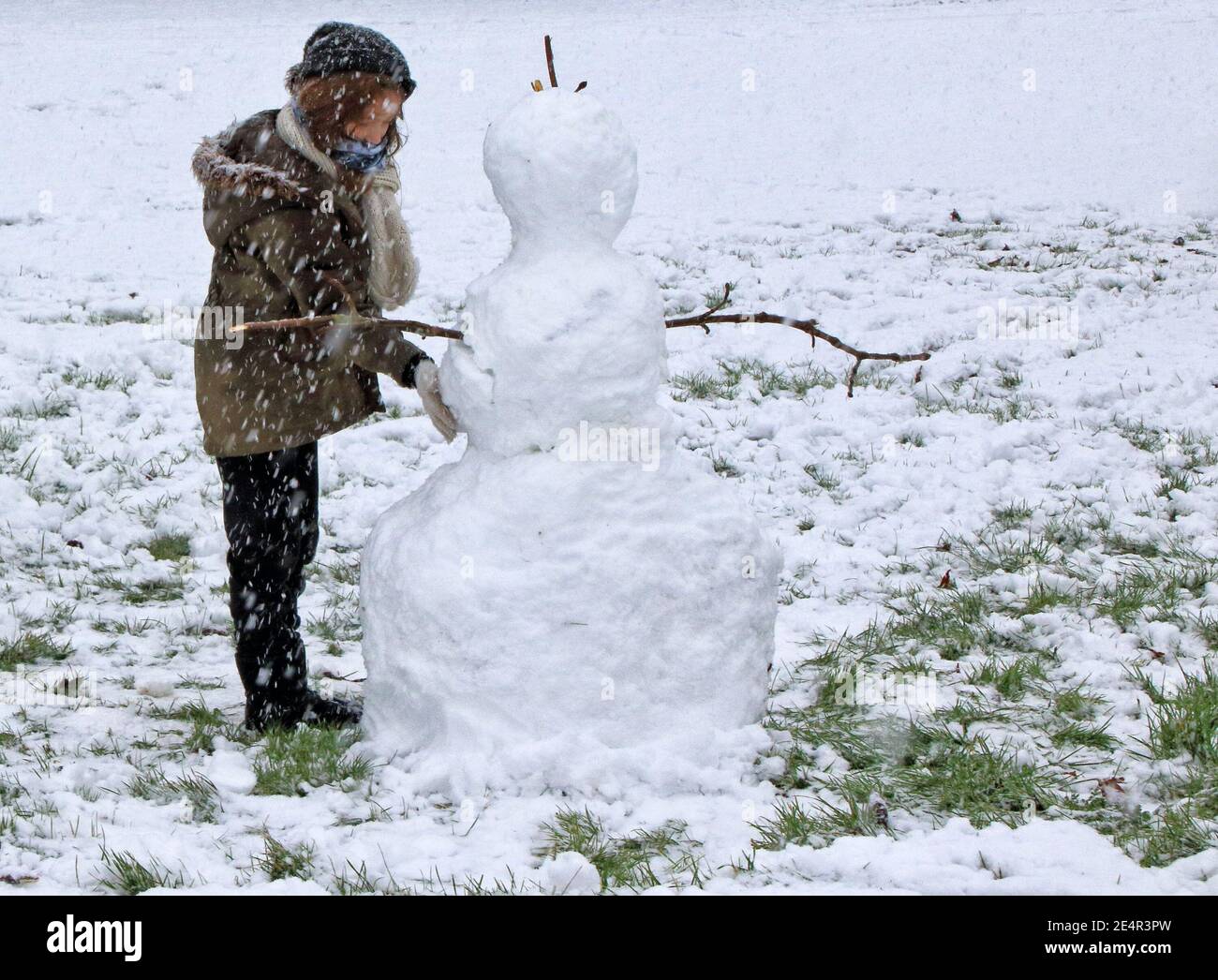 A child seen making final touches to a snowman during the snowfall.With ...