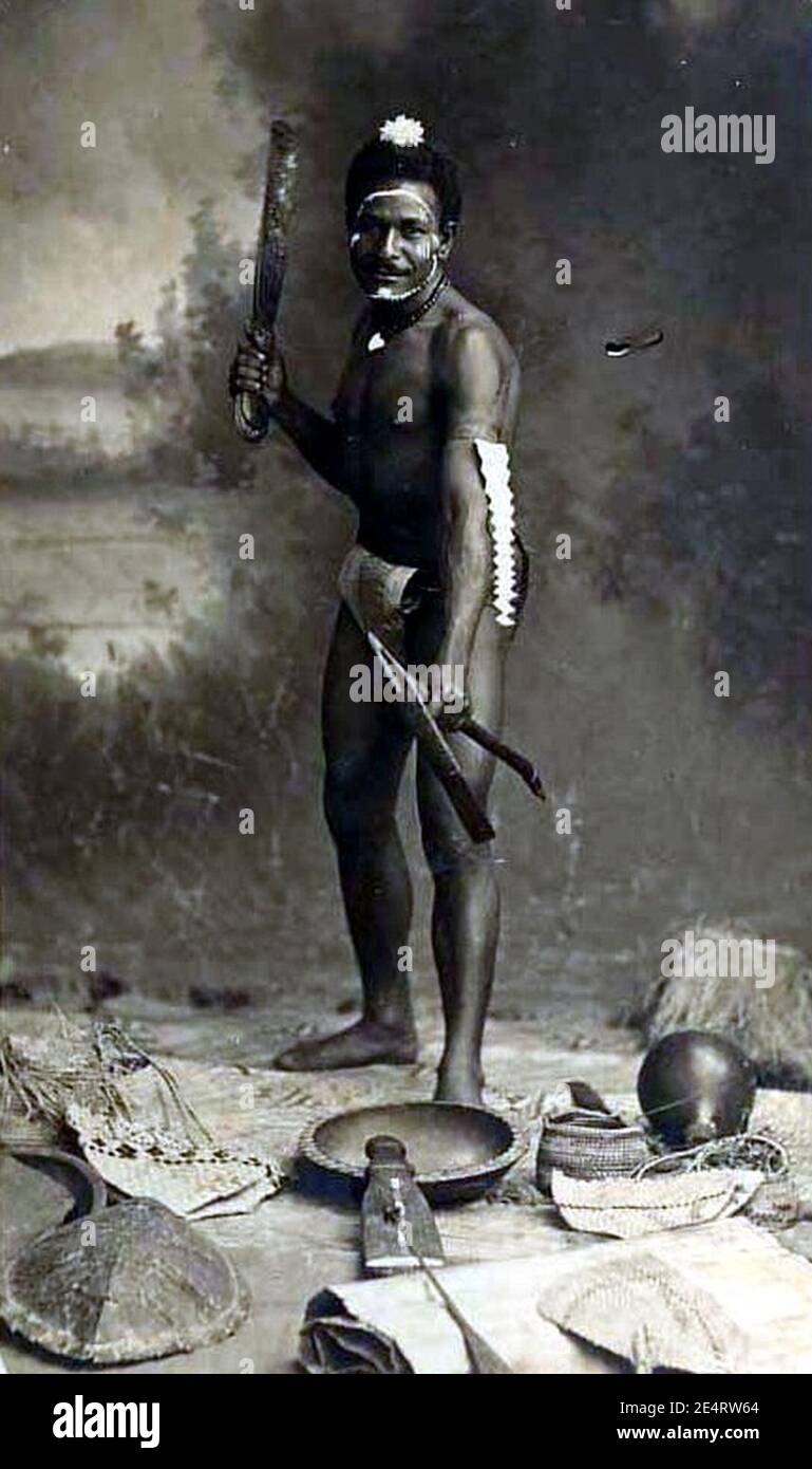 Massim man with sword club, axe and other artefacts, Trobriand Islands ...