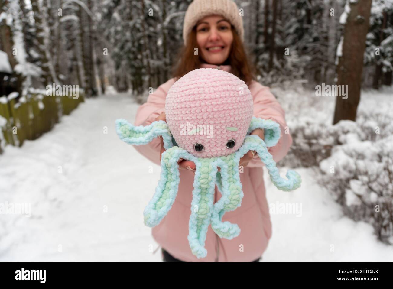 Beautiful girl with a knitted octopus toy in her hands on the street in ...
