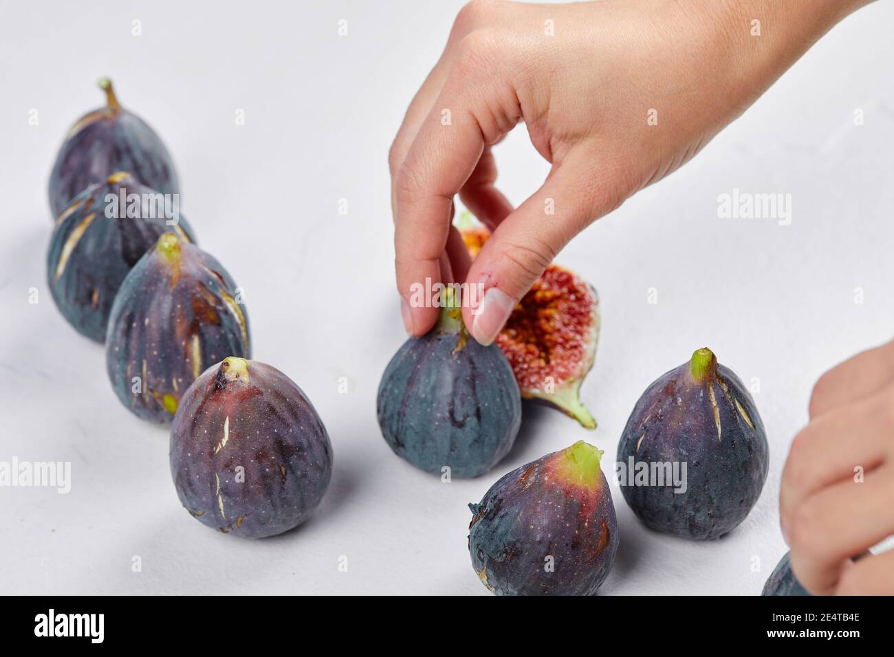 Hand holding a fig and fig slices on a white background Stock Photo - Alamy