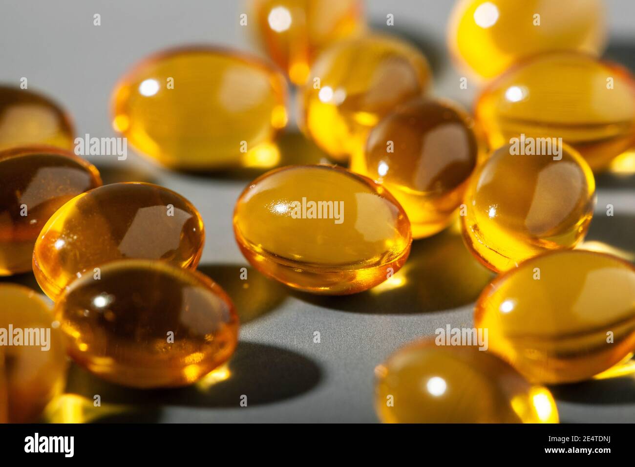Yellow gelatin capsules on a gray background. Food supplement, vitamin ...