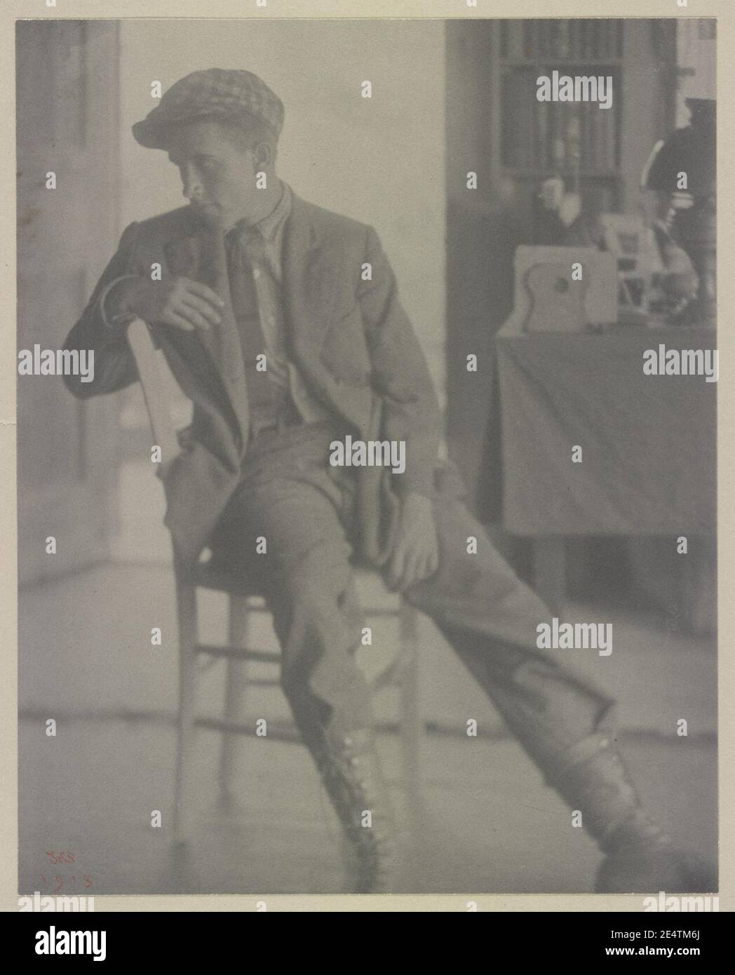 Maynard White in suit, wearing boots and cap, seated Stock Photo - Alamy