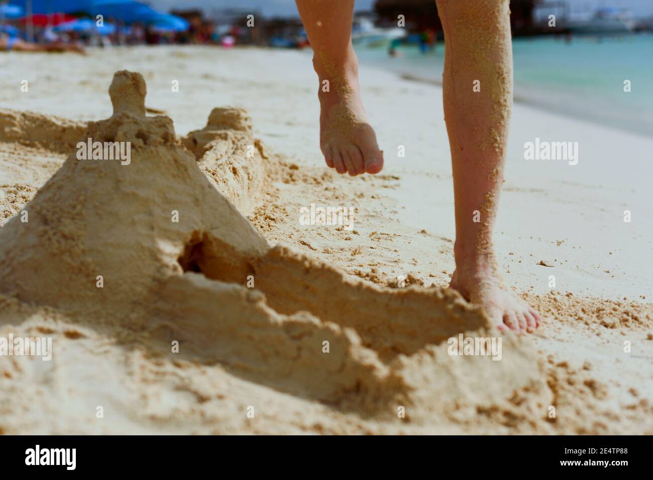 Isla Mujeres, Cancun, Mexico. Child's feet dance around the sand castle ...