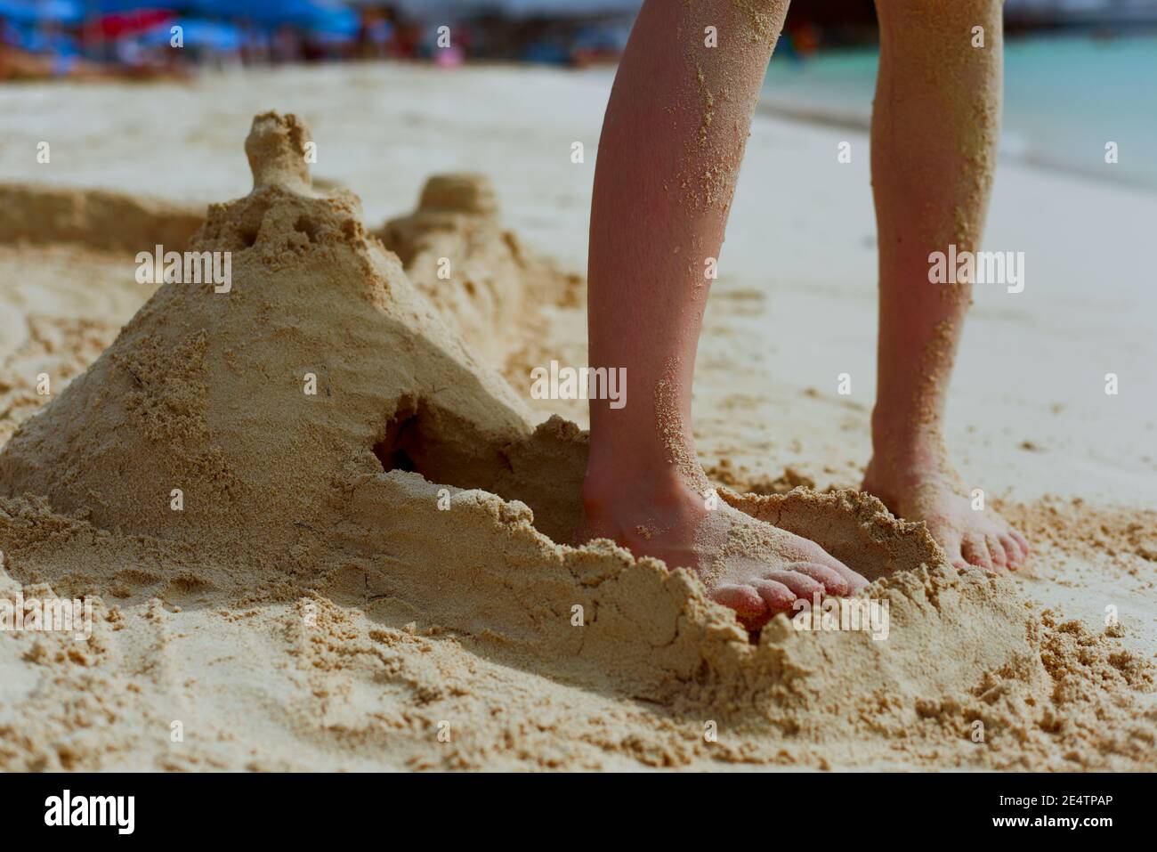 Isla Mujeres, Cancun, Mexico. Child's feet dance around the sand castle ...