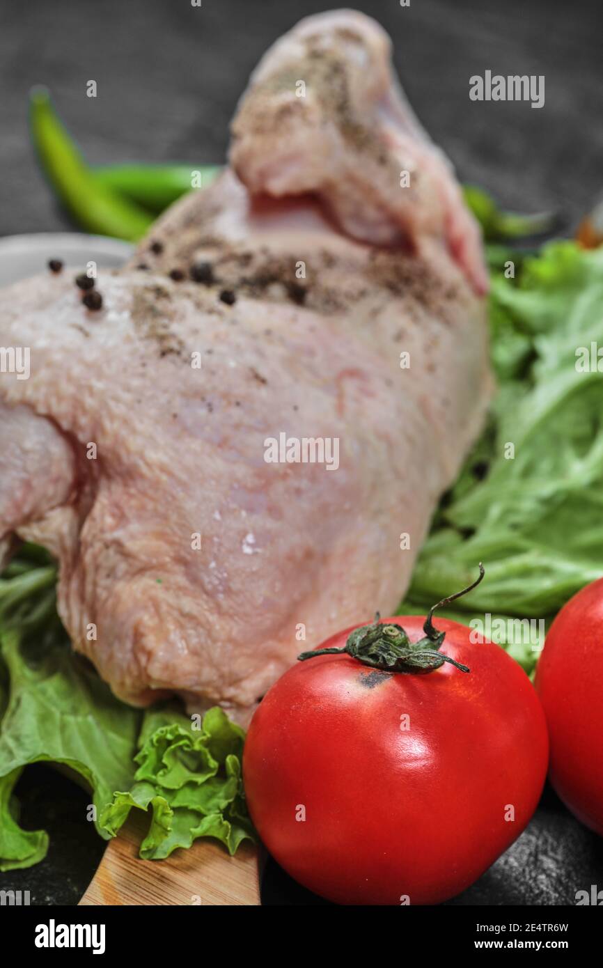 Raw chicken on dark background with bunch of fresh vegetables. Close up ...