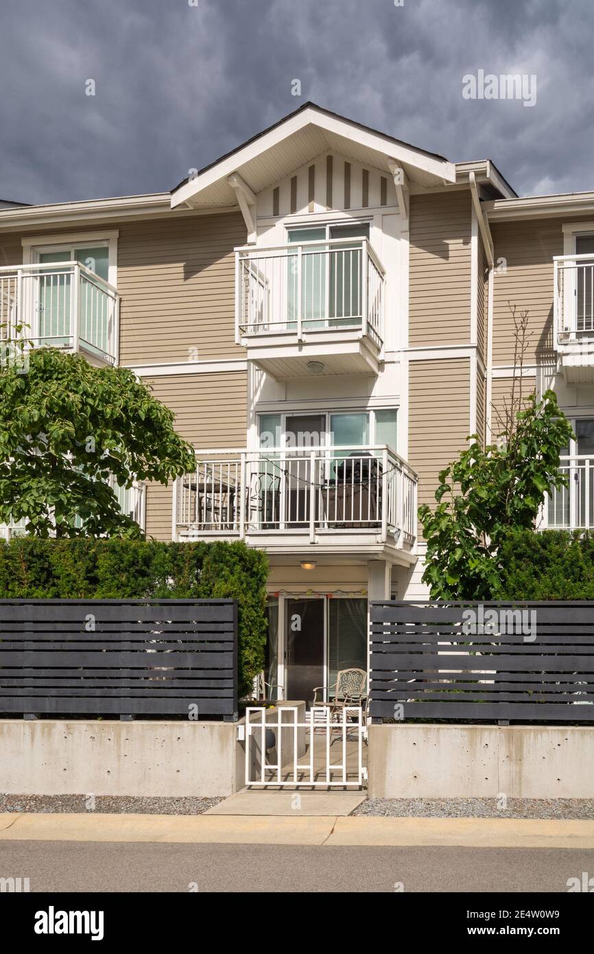 Residential condo building with fenced front yard on stormy sky ...
