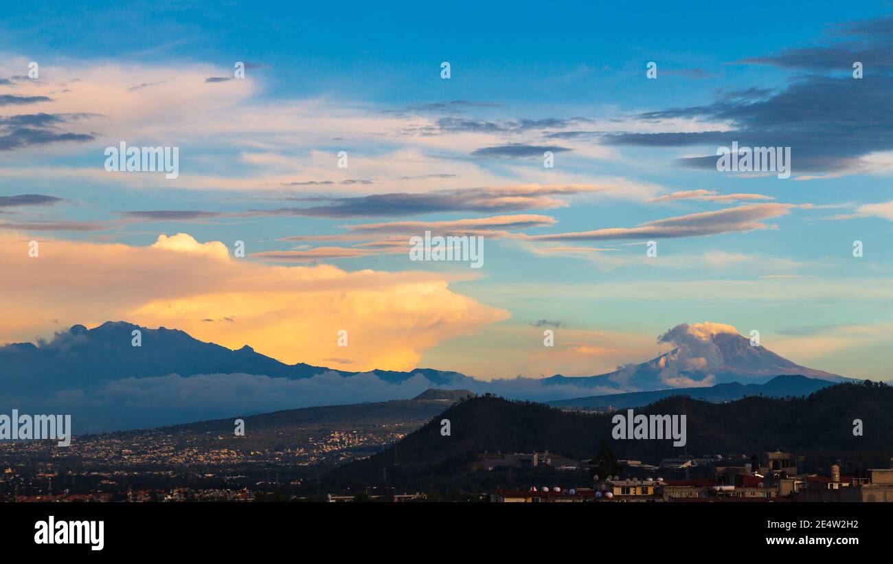 Sun rising behind the volcanoes, with some clouds and a blue sky Stock ...