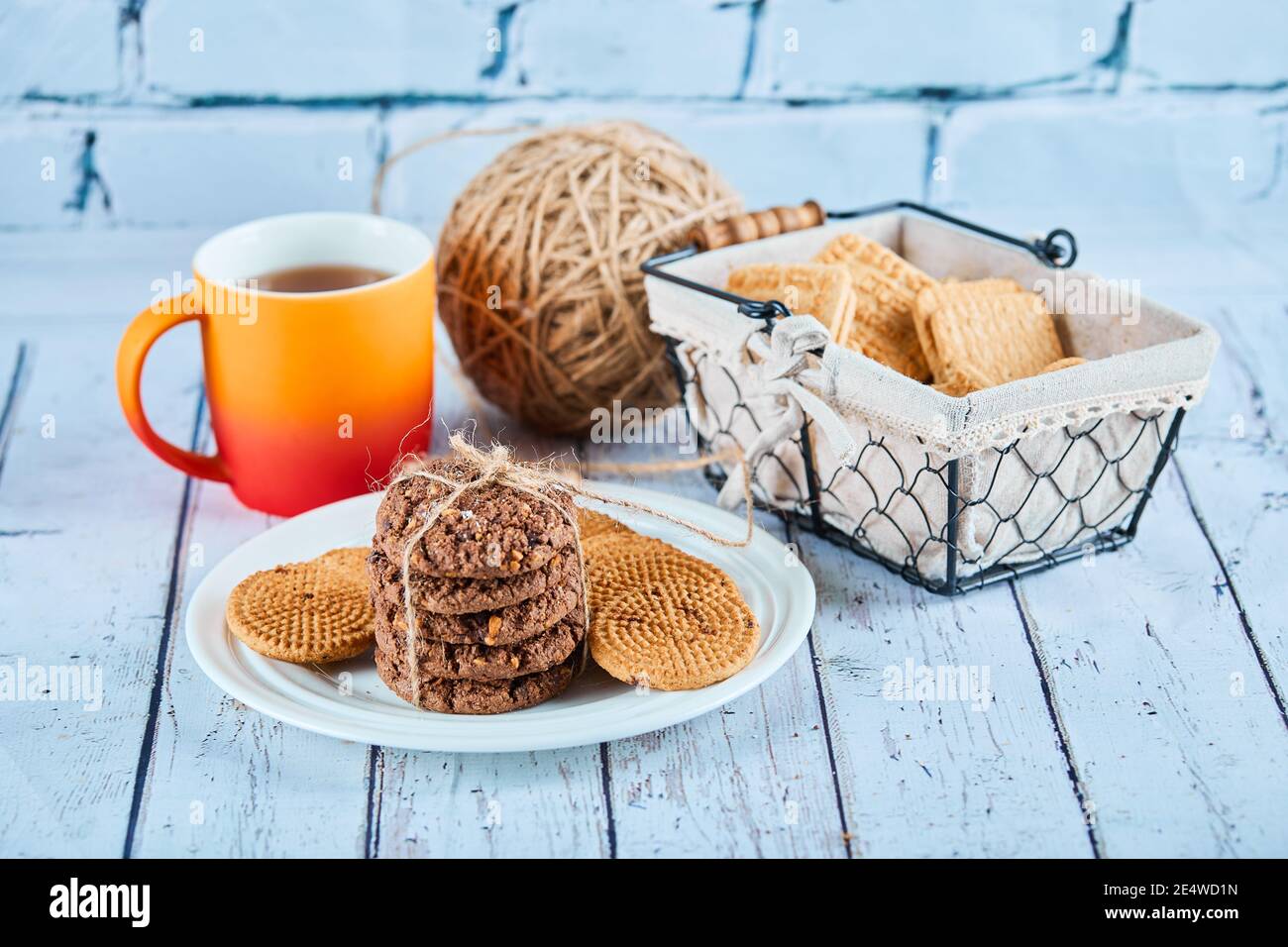 Assorted biscuits in plate and basket and a cup on blue table Stock ...