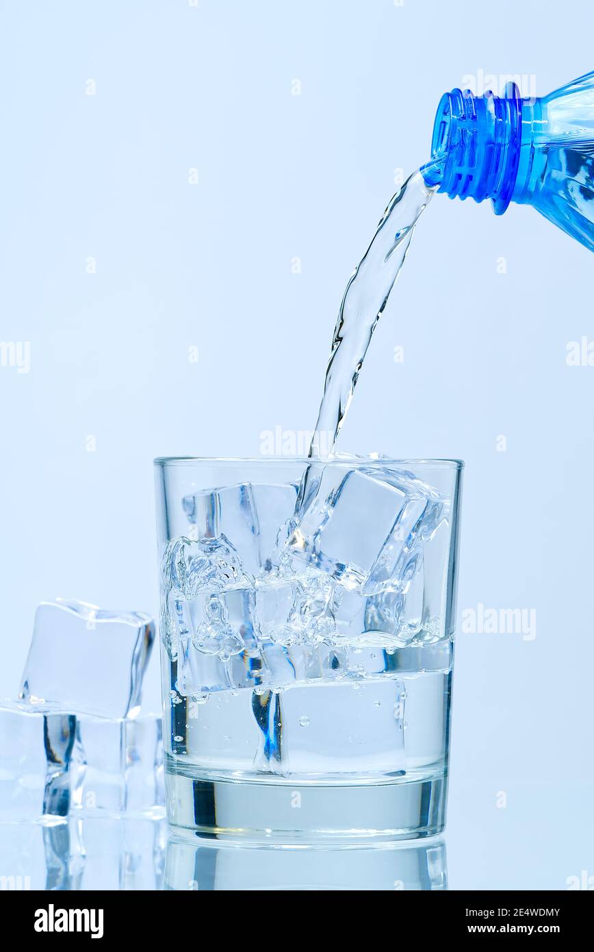 Pouring clean drinking water from blue plastic bottle into glass on ...