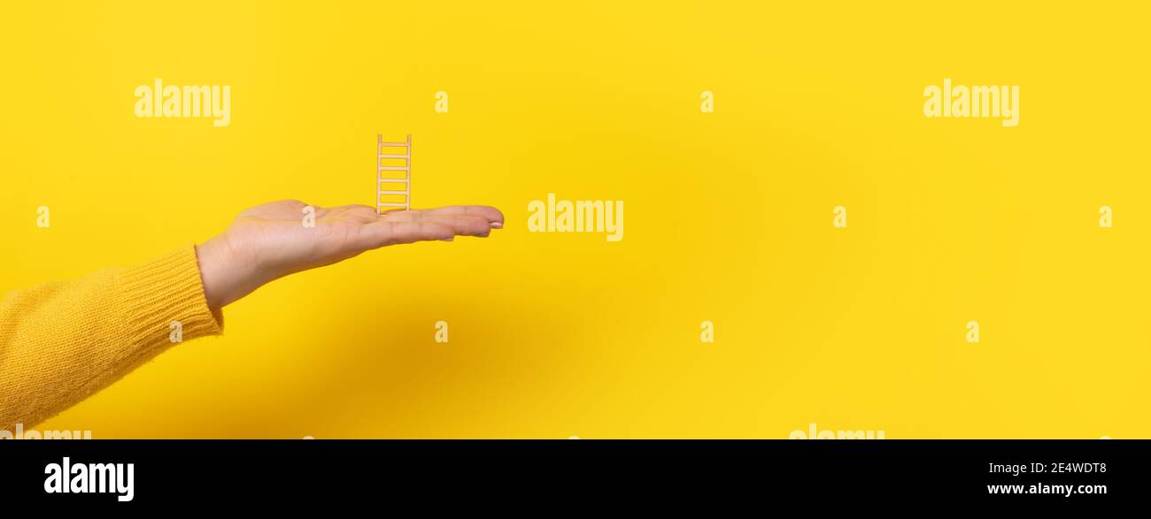 hand holding a ladder over yellow background, education and success ...