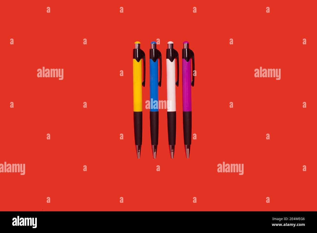 four colored pens lying on a red background Stock Photo - Alamy