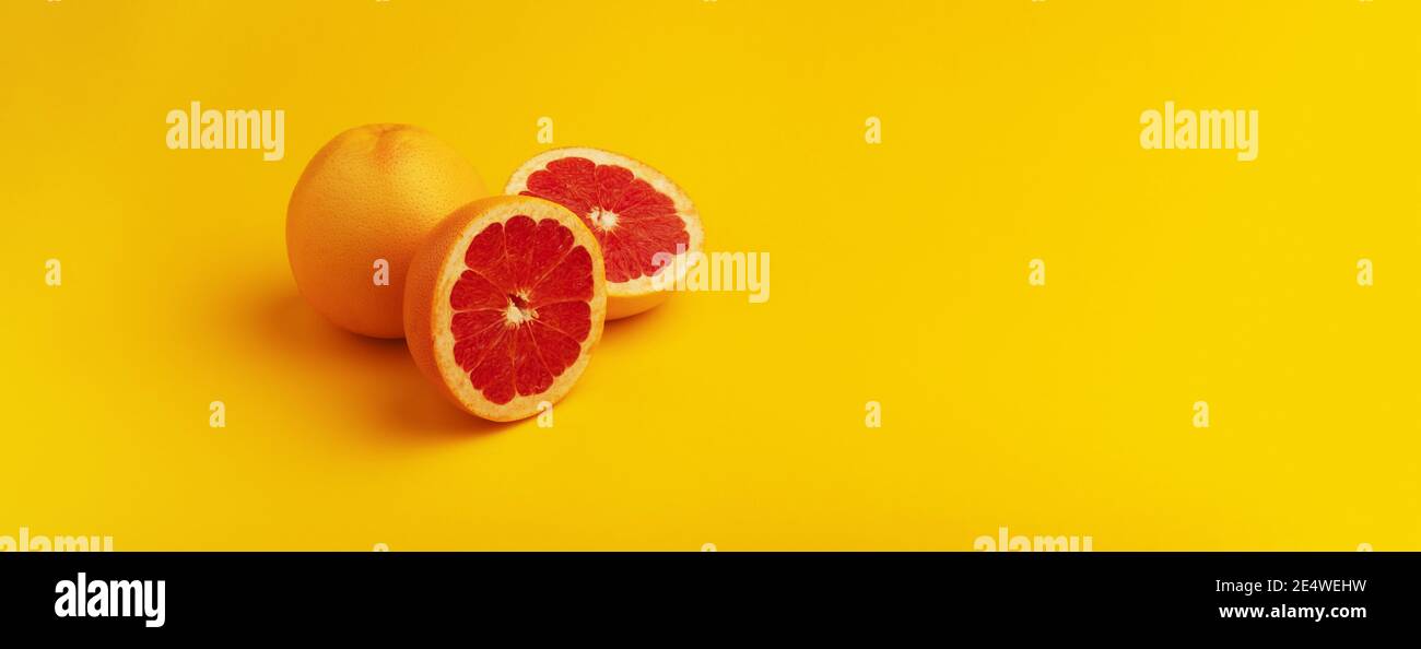 Whole and sliced grapefruit over yellow background, panoramic image ...