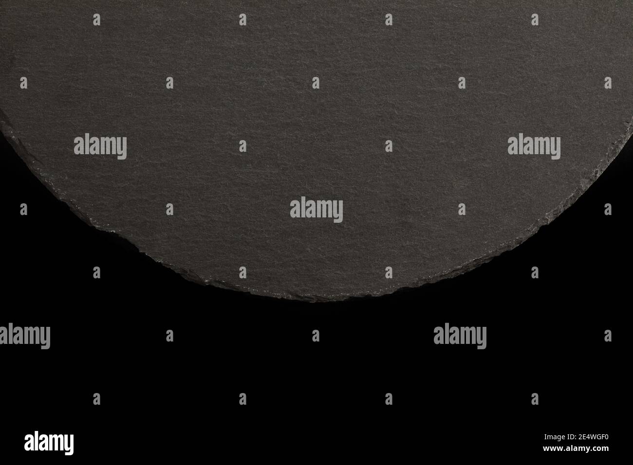 round slate plate over black background Stock Photo - Alamy