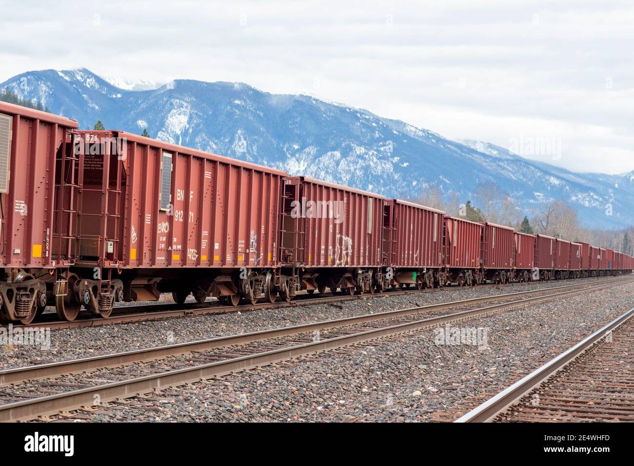 A line of railroad hopper cars on the tracks at the BNSF train yard, in ...
